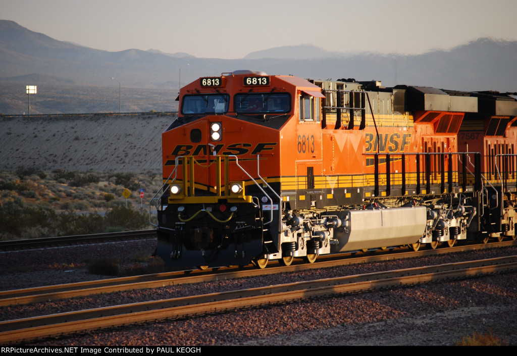 BNSF 6813 ith the Rising Sun Gleeming off her Brand New BNSF Swoosh Logo Paint heads west.
